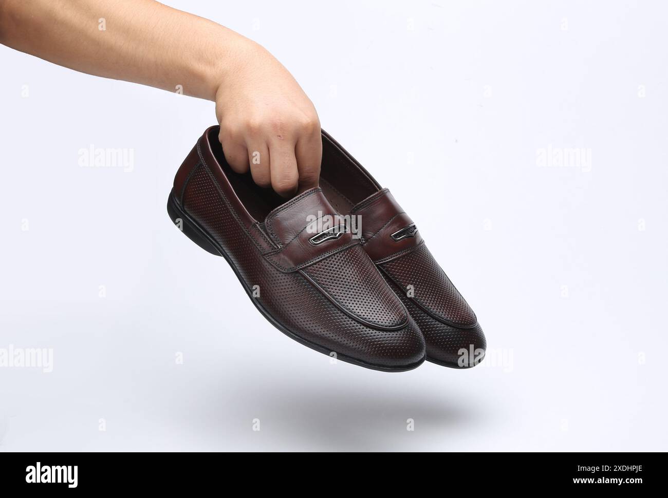 Hand holding pair of modern leather moccasins shoes on white background ...