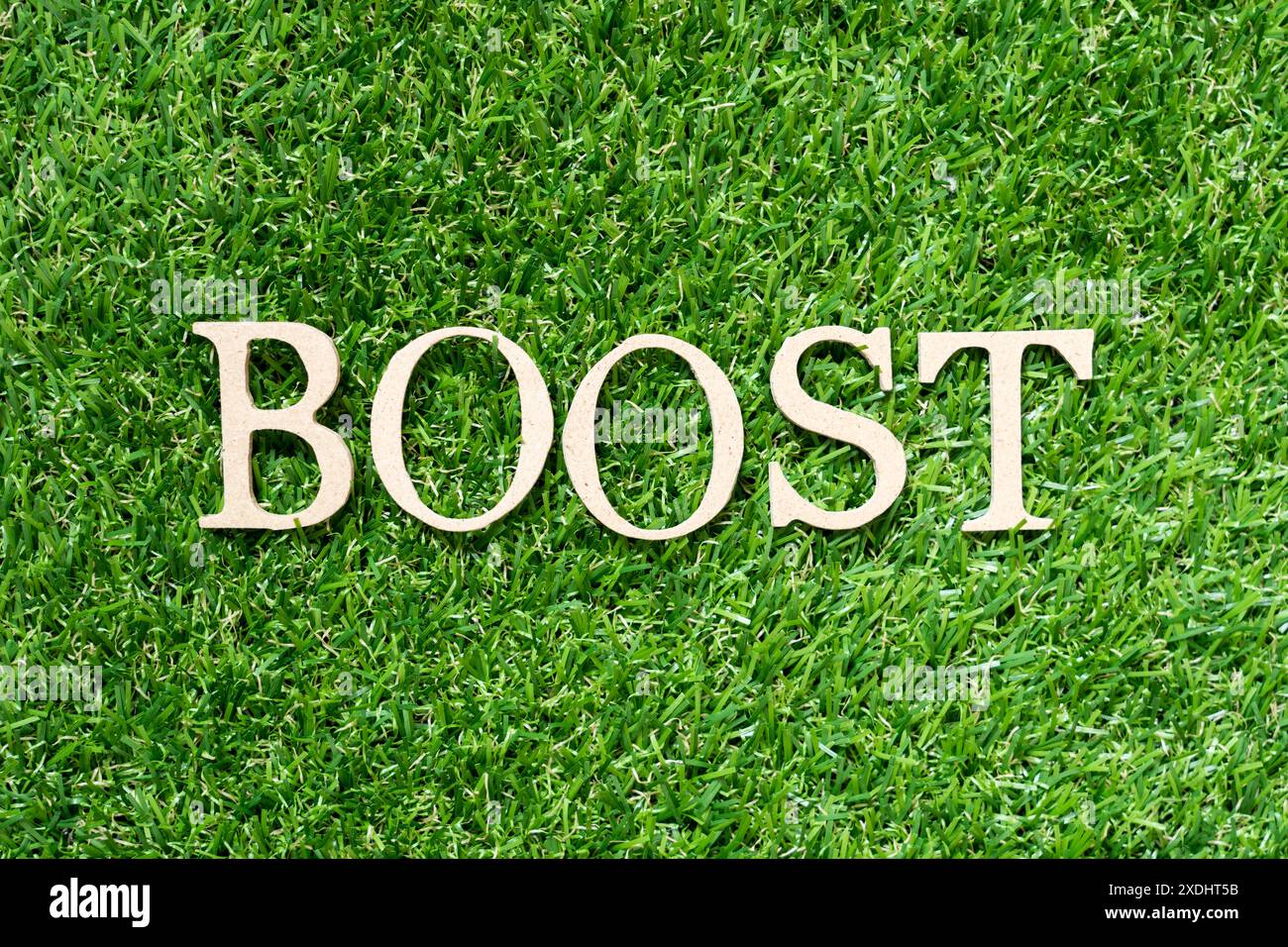 Wood alphabet letter in word boost on artificial green grass background ...