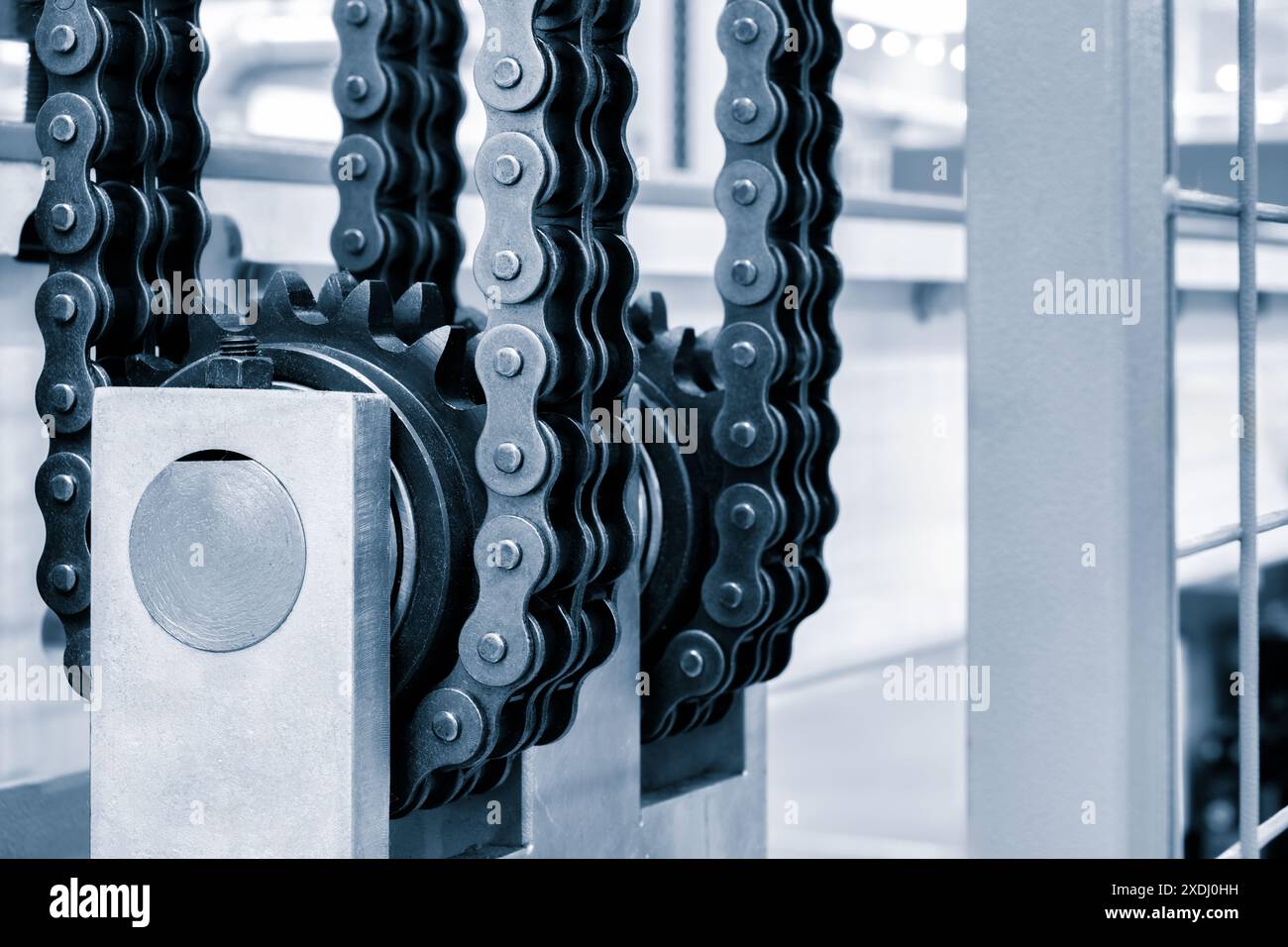 A chain is shown in a factory setting. The chain is black and silver ...