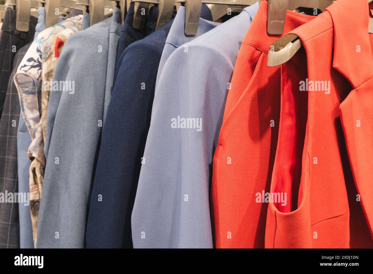 A rack of clothes with a blue jacket on the left and a red jacket on ...