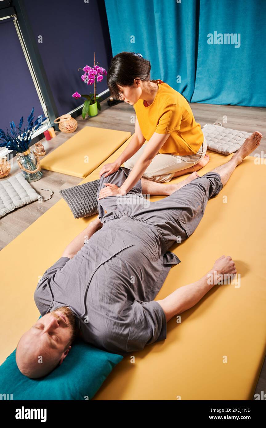Masseuse making thai yoga massage. Woman therapist doing traditional ...