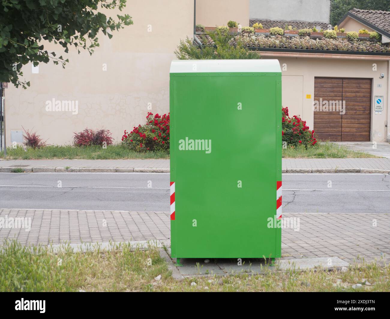 Large green metal waste container standing on a street for clothing ...