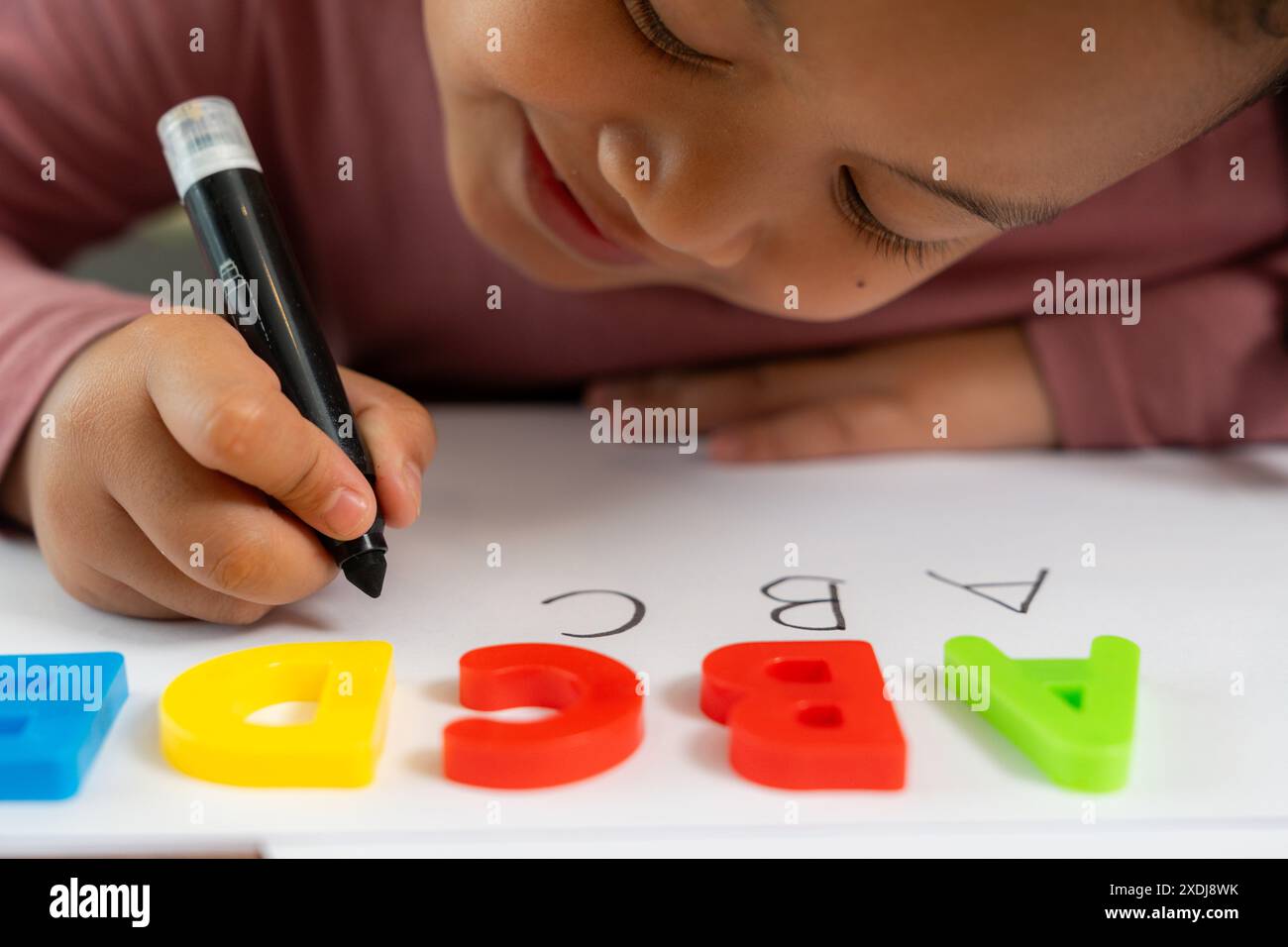 A little girl happily practicing writing the letters A, B, C Stock ...