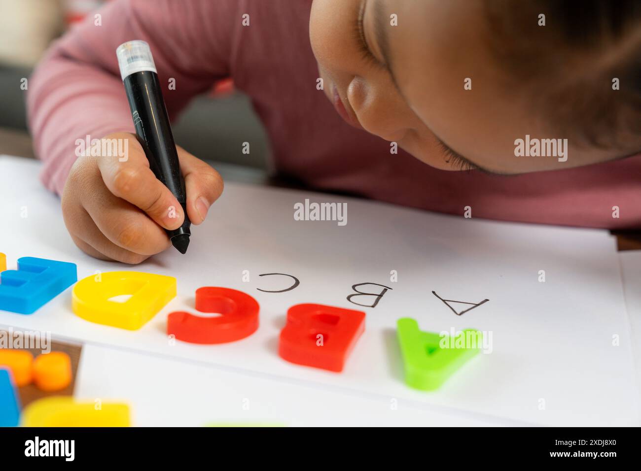 A little girl happily practicing writing the letters A, B, C Stock ...