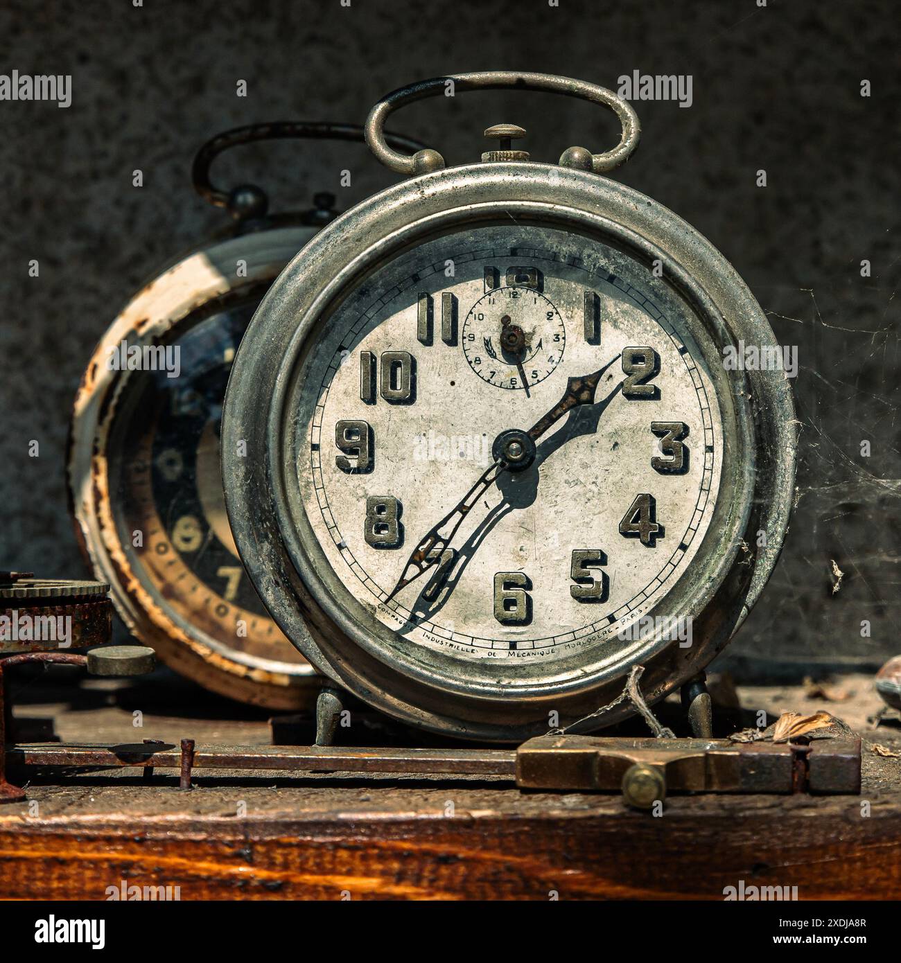 Old vintage alarm clock with sunlit dial on a shelf with old tools ...