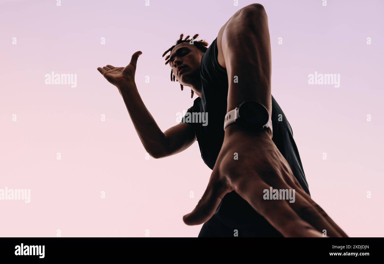 Gen Z man wearing earbuds and a smartwatch dances energetically in a ...