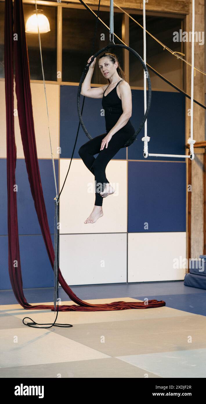 Woman sitting on an aerial hoop in a studio, preparing to perform ...