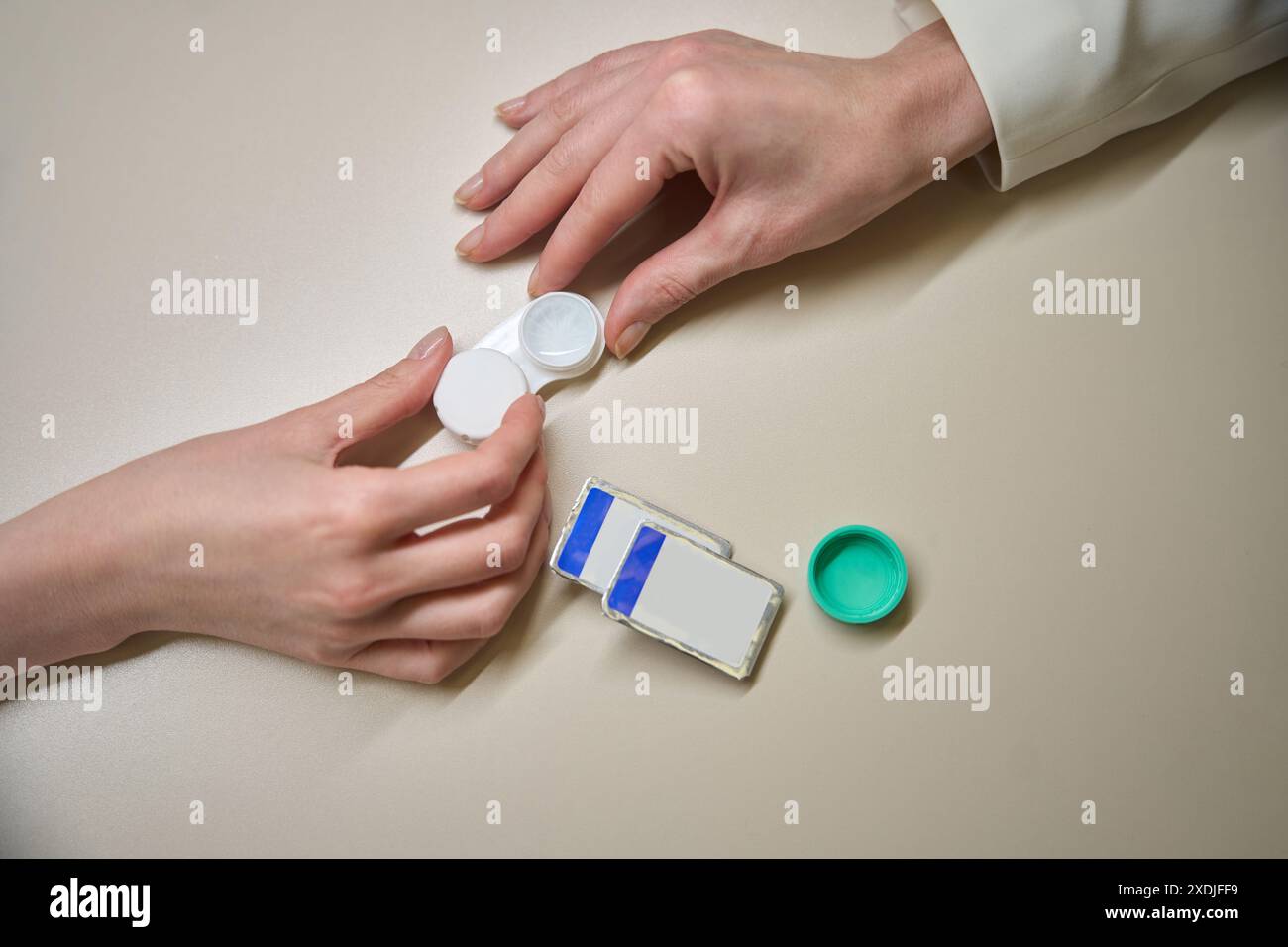 Female hands a container with lenses to another woman Stock Photo - Alamy