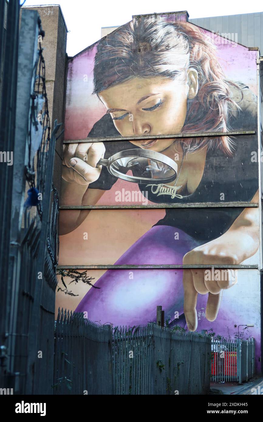 Giant mural painting of a girl with a magnifying glass, looking down to ...