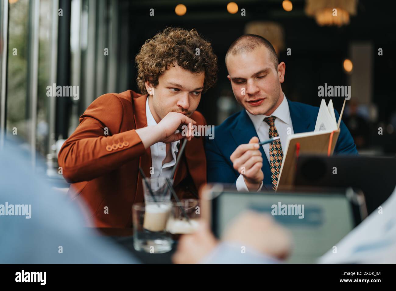 Two businessmen discussing ideas while reviewing documents in a modern ...