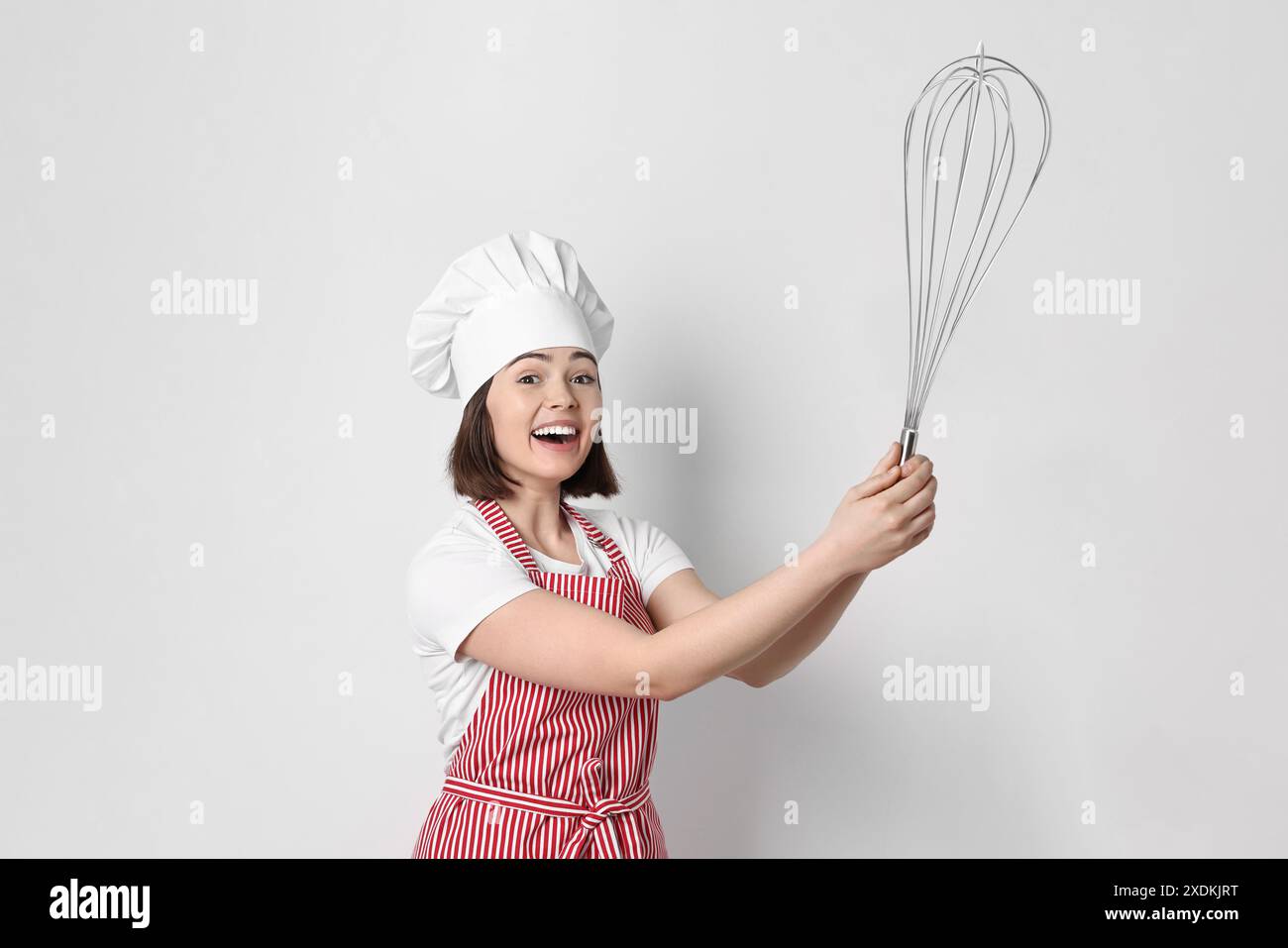 Happy pastry chef with big whisk on light background Stock Photo - Alamy
