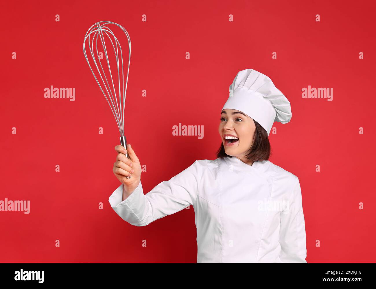 Happy pastry chef with big whisk on red background Stock Photo - Alamy
