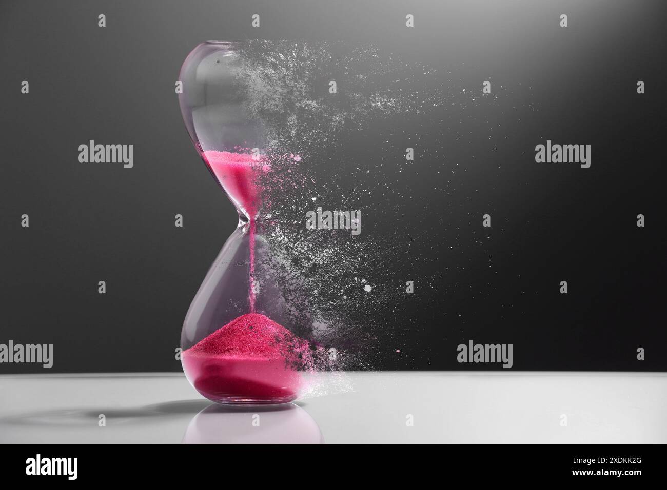 Hourglass dissolving on table against dark background. Fleeting time ... Hourglass dissolving on table against dark background. Fleeting time ...