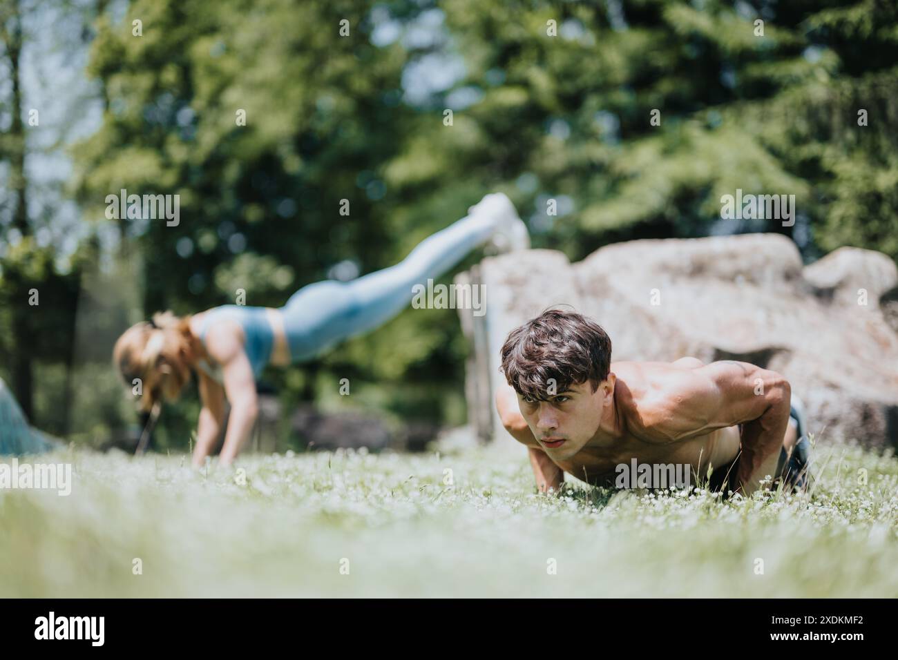 Young adults performing outdoor calisthenics and push-ups in a park ...