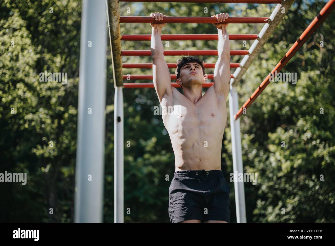 Fit man doing calisthenics exercises at urban park on monkey bars Stock ...
