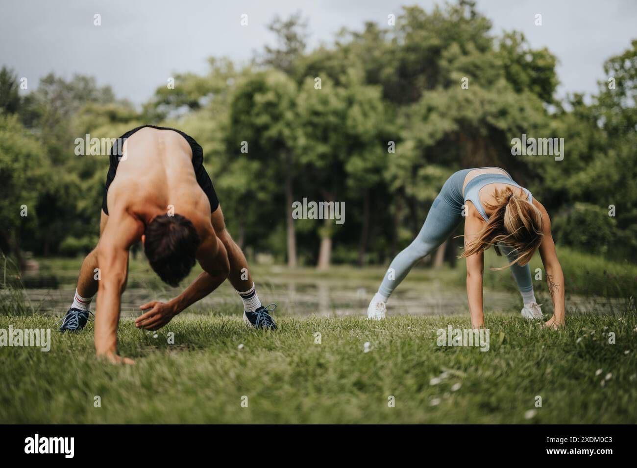 Two people doing outdoor exercise together in nature, stretching and ...