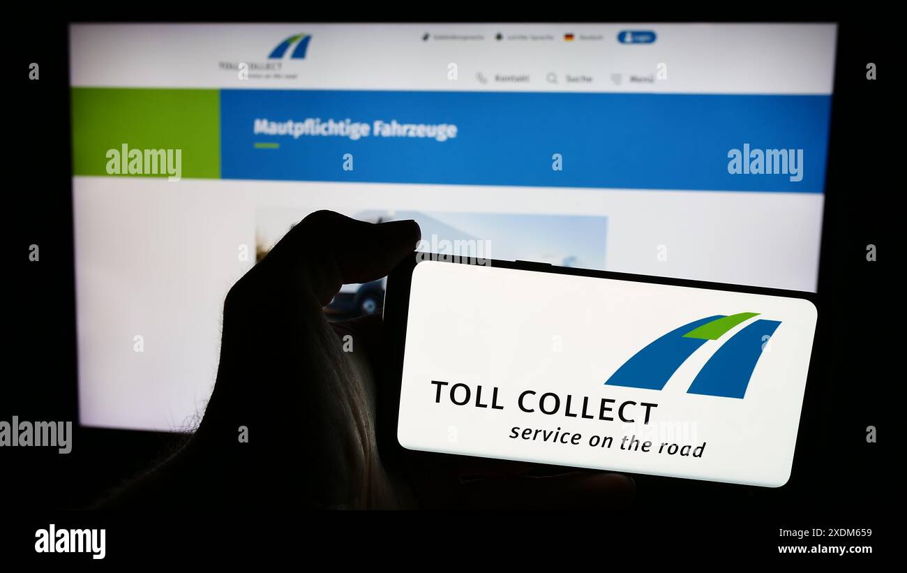 Person holding mobile phone with logo of German autobahn tolling system ...