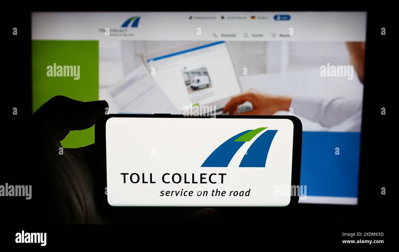 Person holding cellphone with logo of German autobahn tolling system ...
