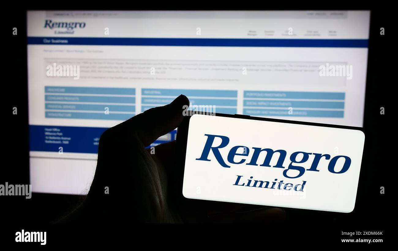 Person holding mobile phone with logo of South African investment ...