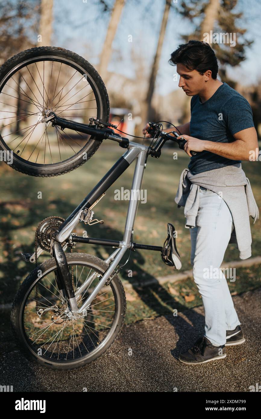 Active man checking his bicycle in the sunny park, outdoor cycling ...