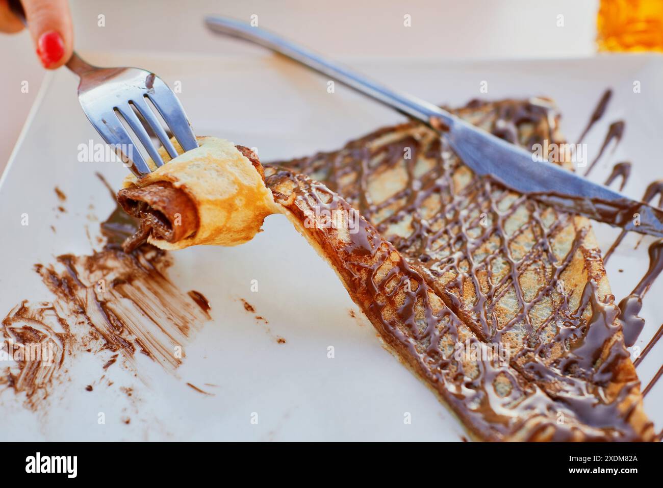 eating a piece of crepe on a plate Stock Photo - Alamy