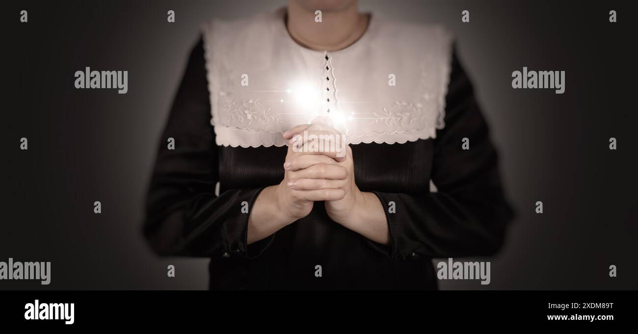 A nun dressed in traditional attire is seen praying with her hands ...