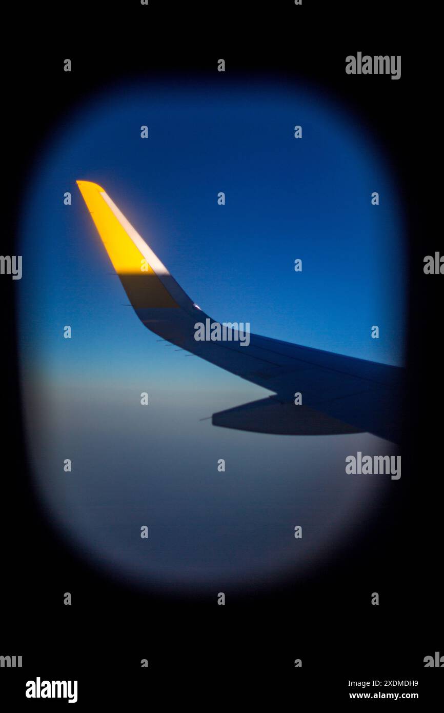 Airplane wing end illuminated by the rising sun through a window at ...