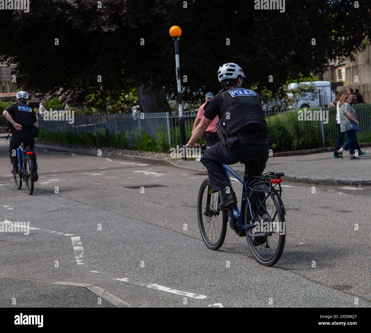 Two police officers in uniform patrolling a city street on bicycles ...