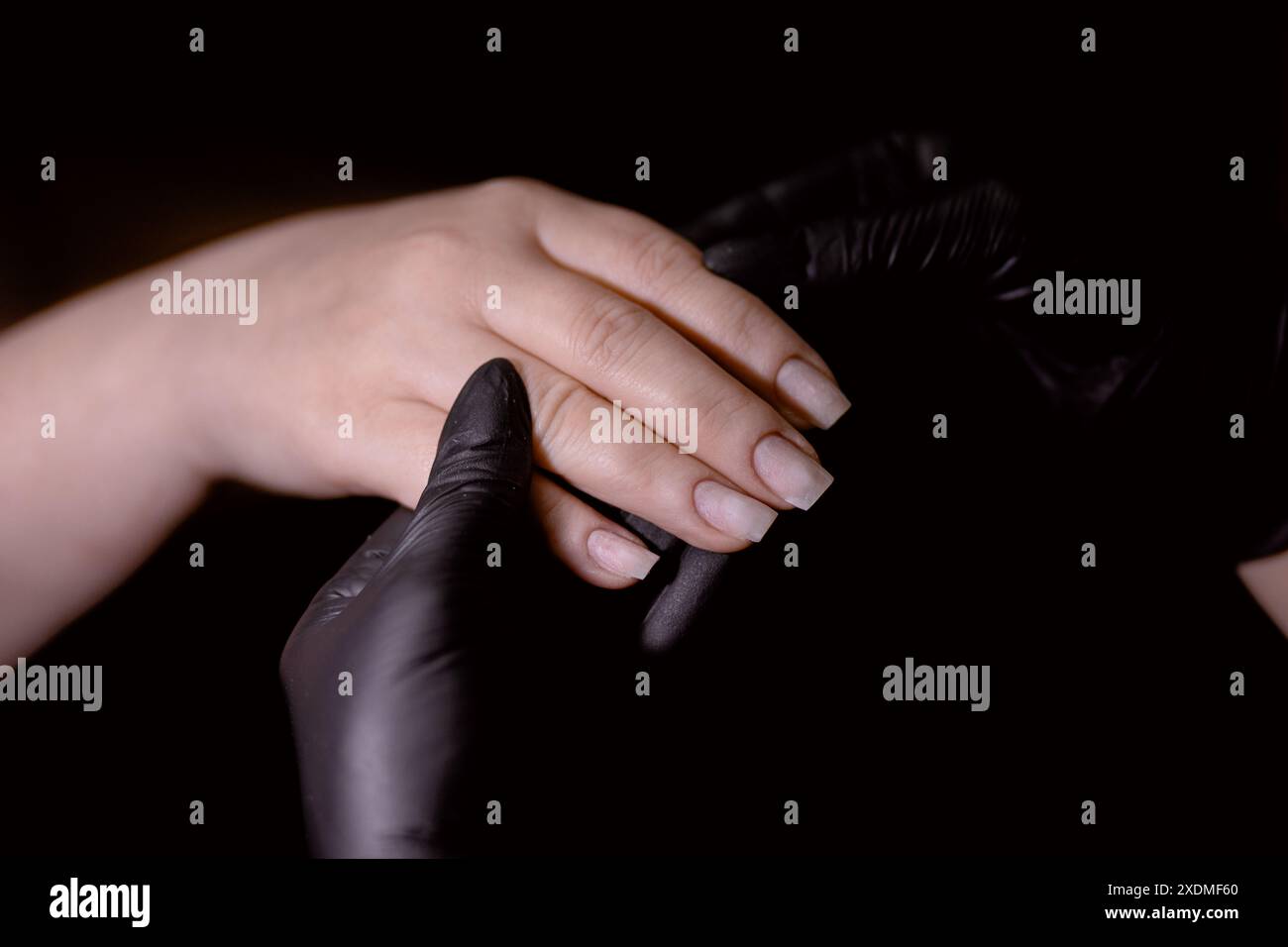 Manicure finish. Technician in black gloves inspecting finished nails ...