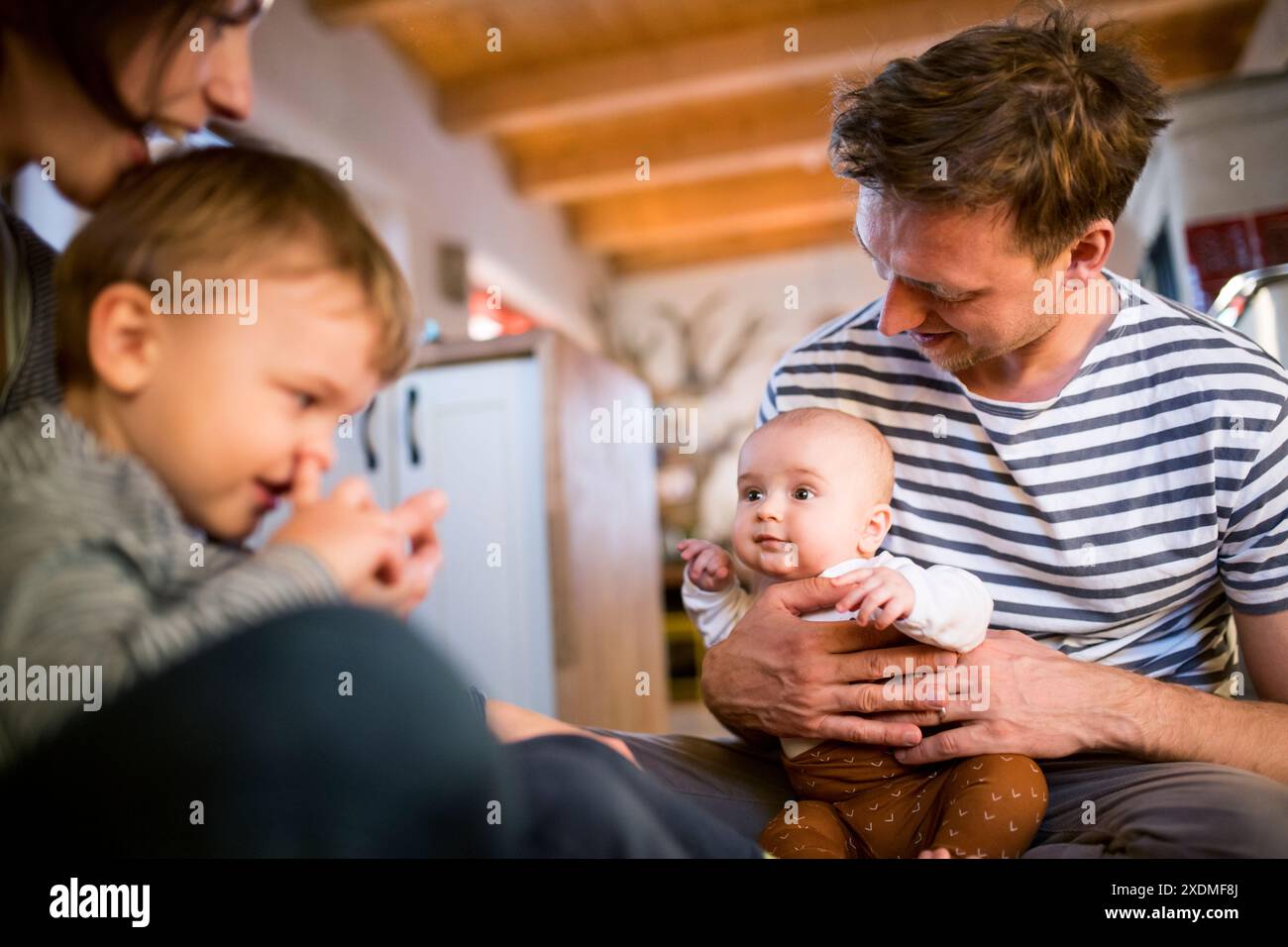 Happy parents holding small baby and playing with his older brother ...