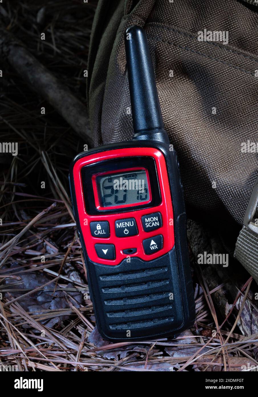 Red colored small GMRS two way transceiver outdoors resting on a brown ...