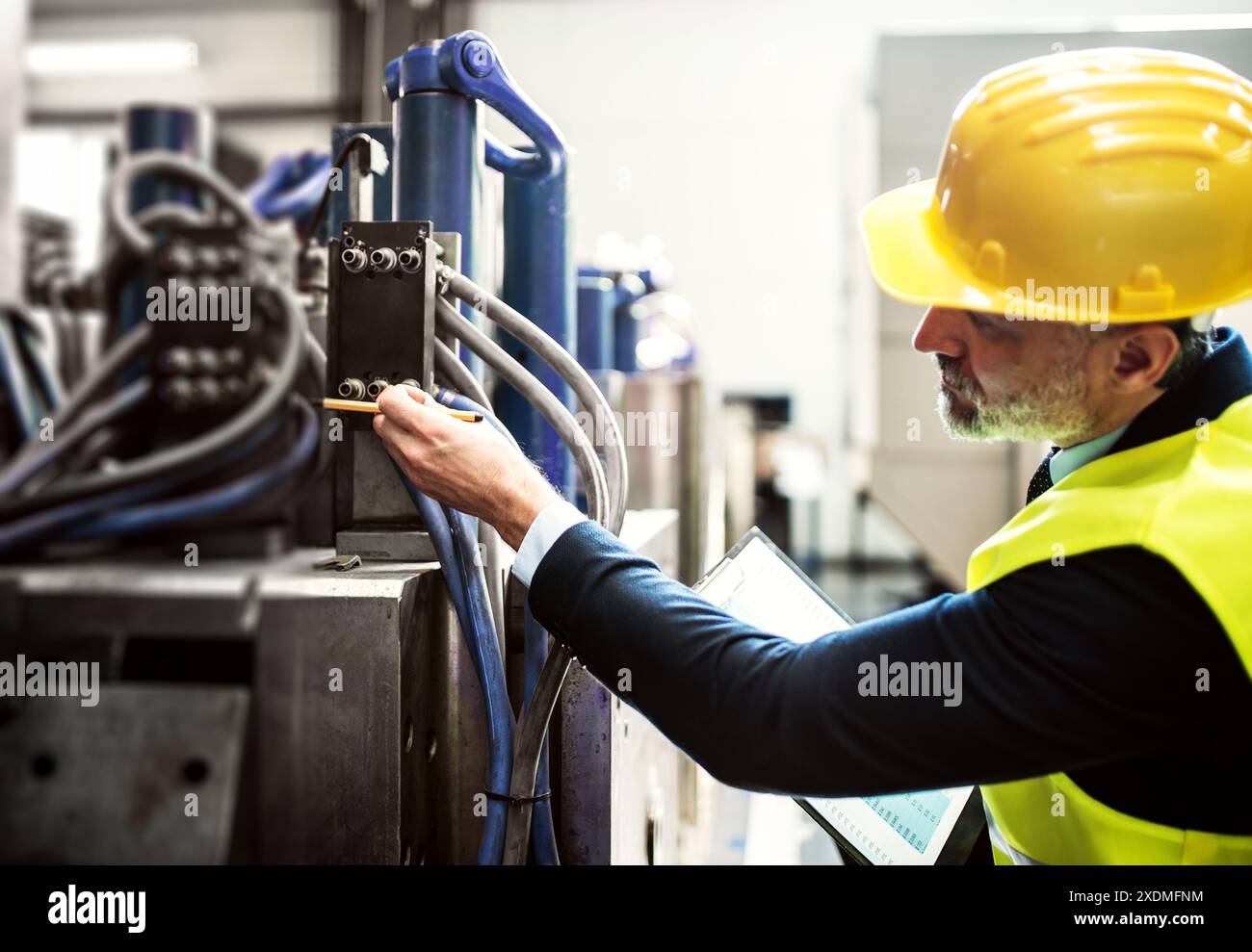 Portrait of engineer controlling machine in modern industrial factory ...