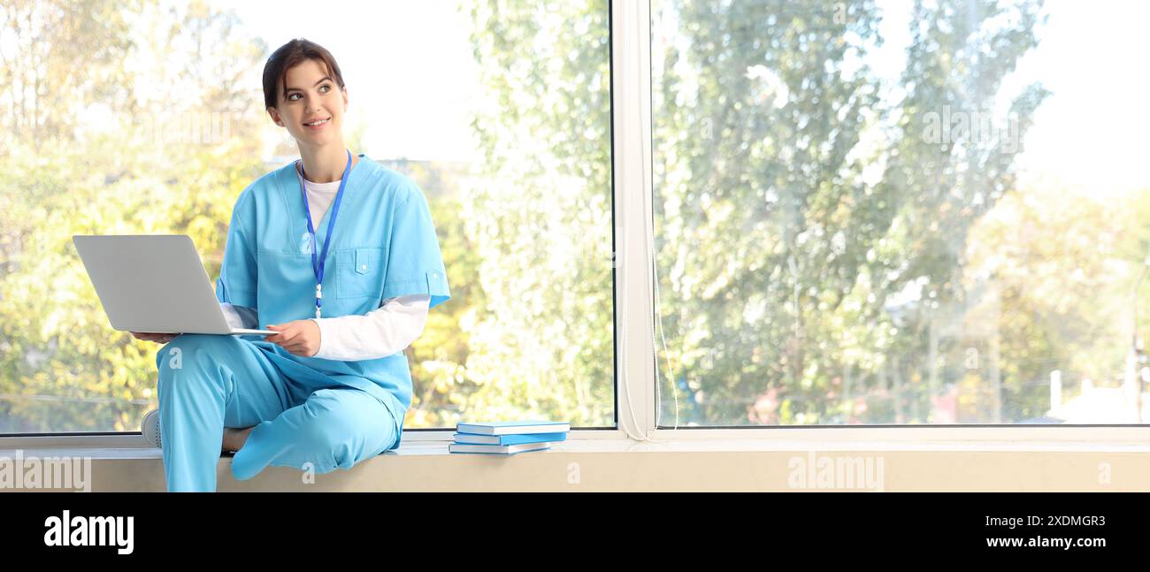 Female medical intern with laptop sitting on window sill. Banner for ...