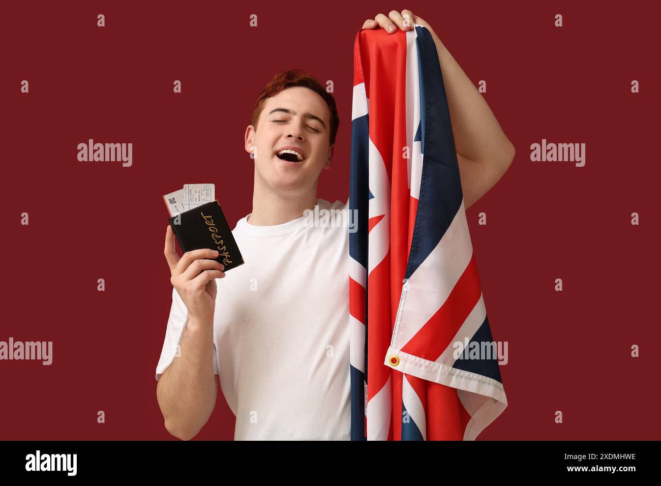 Handsome young happy man with UK flag, passport and tickets on red ...