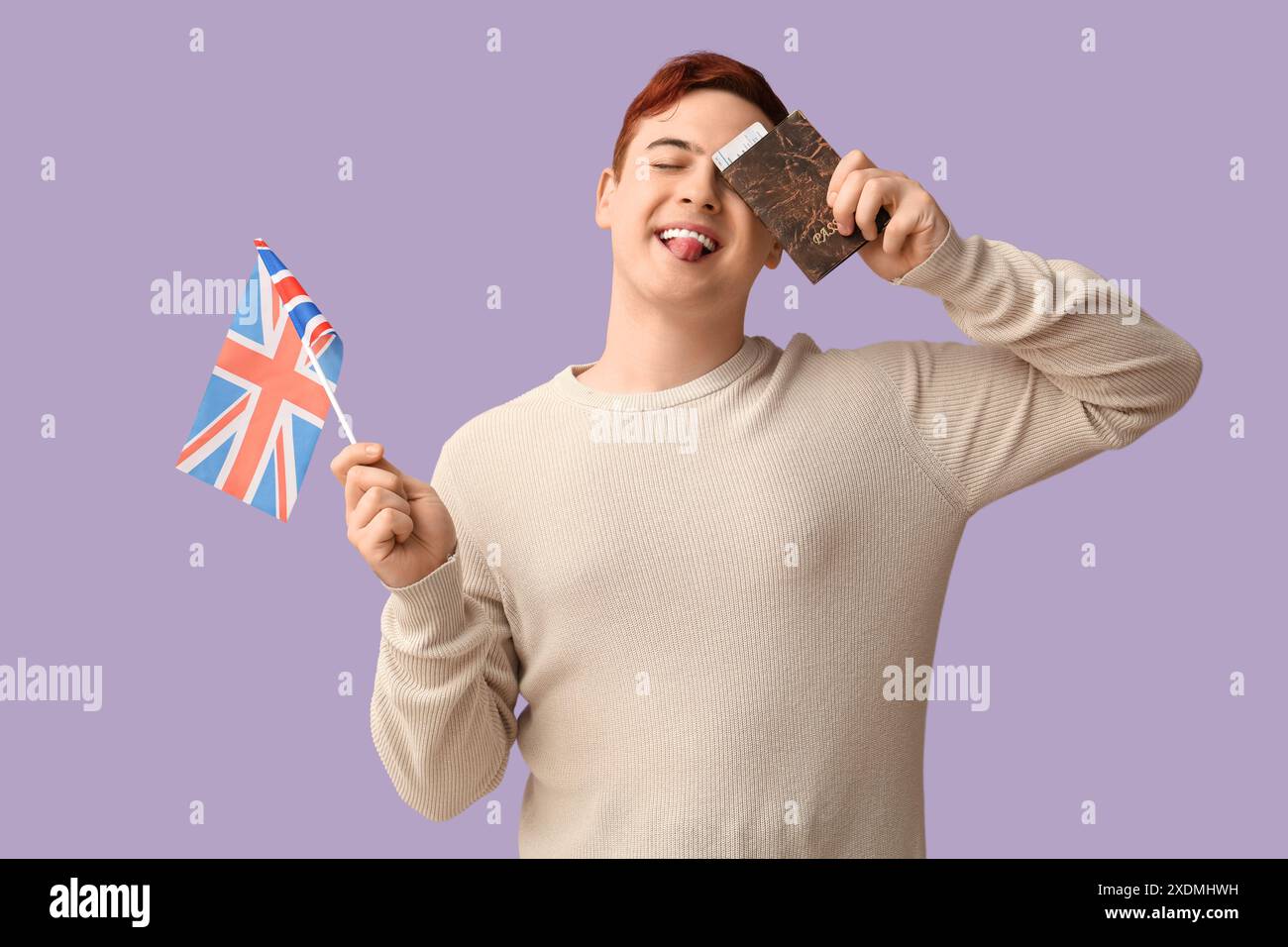 Handsome young happy man with UK flag, passport and ticket on purple ...