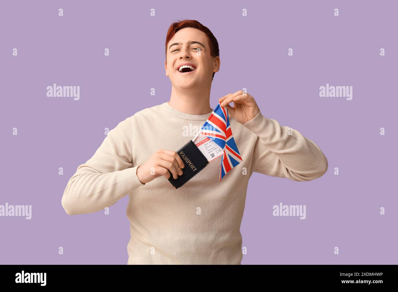 Handsome young happy man with UK flag, passport and tickets on purple ...
