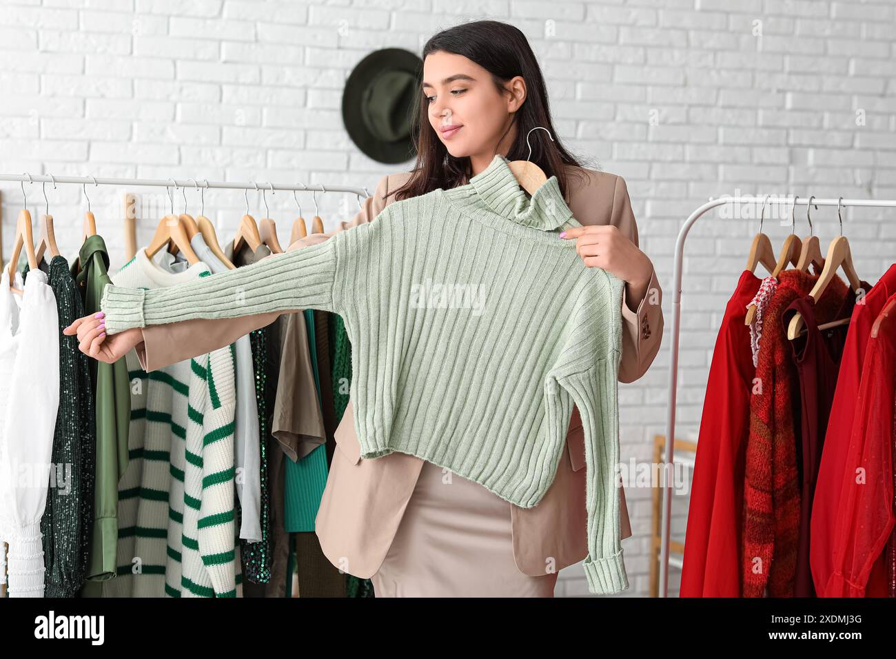 Happy female stylist with clothes on rack in studio Stock Photo - Alamy