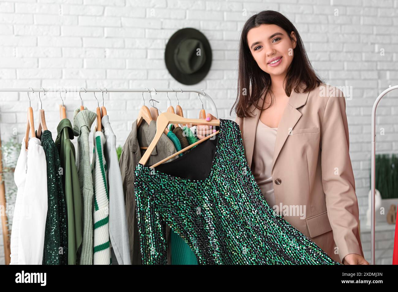 Happy female stylist with clothes on rack in studio Stock Photo - Alamy