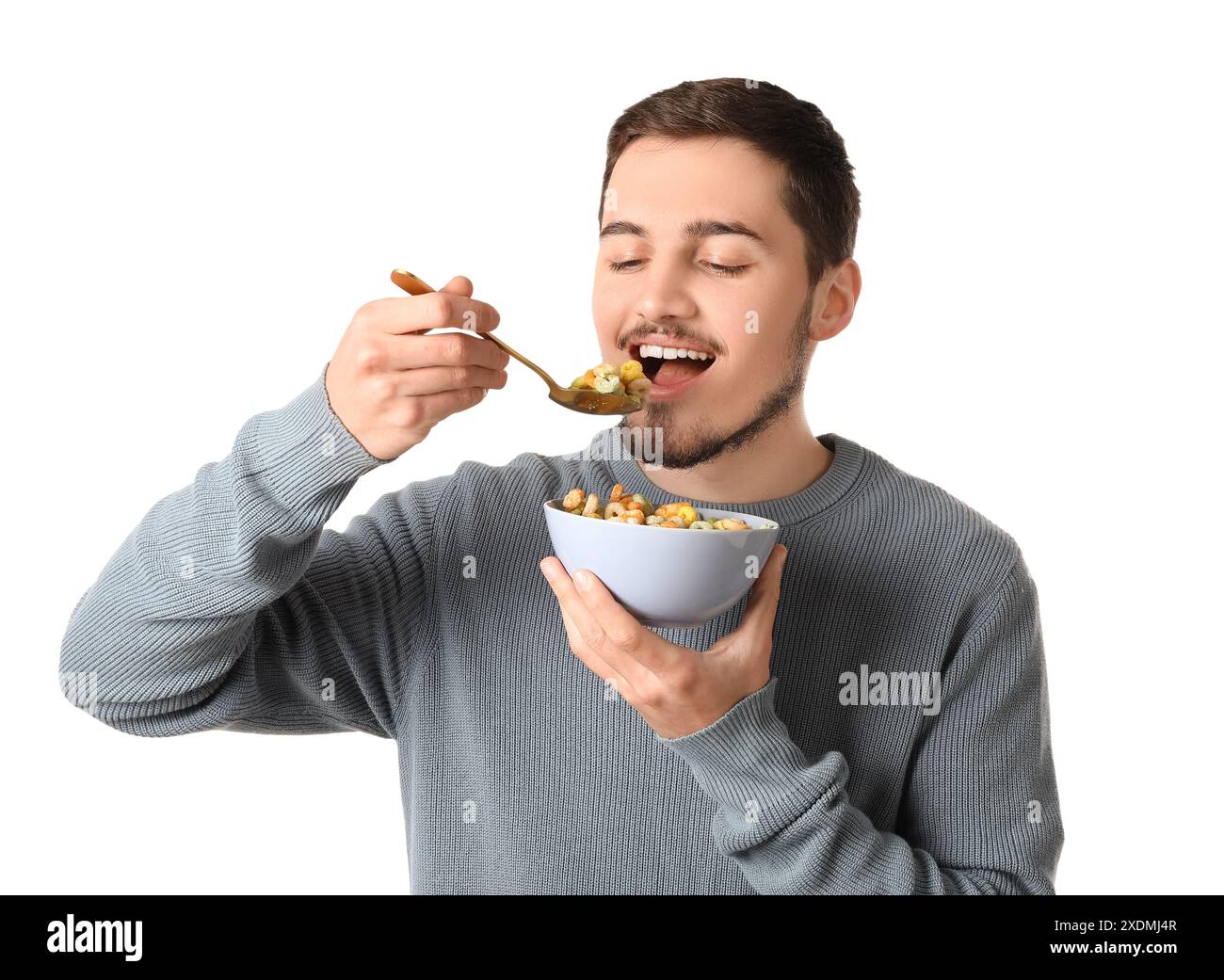 Handsome young man eating tasty cereal rings on white background Stock ...