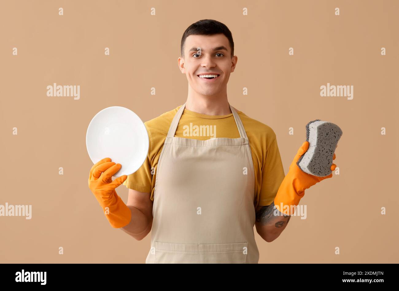 Young tattooed man with plate and sponge on beige background Stock ...