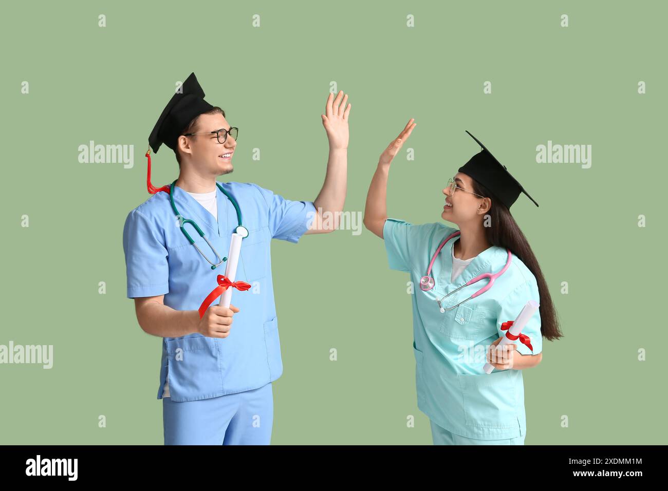 Happy medical graduate couple with diplomas and stethoscopes giving ...
