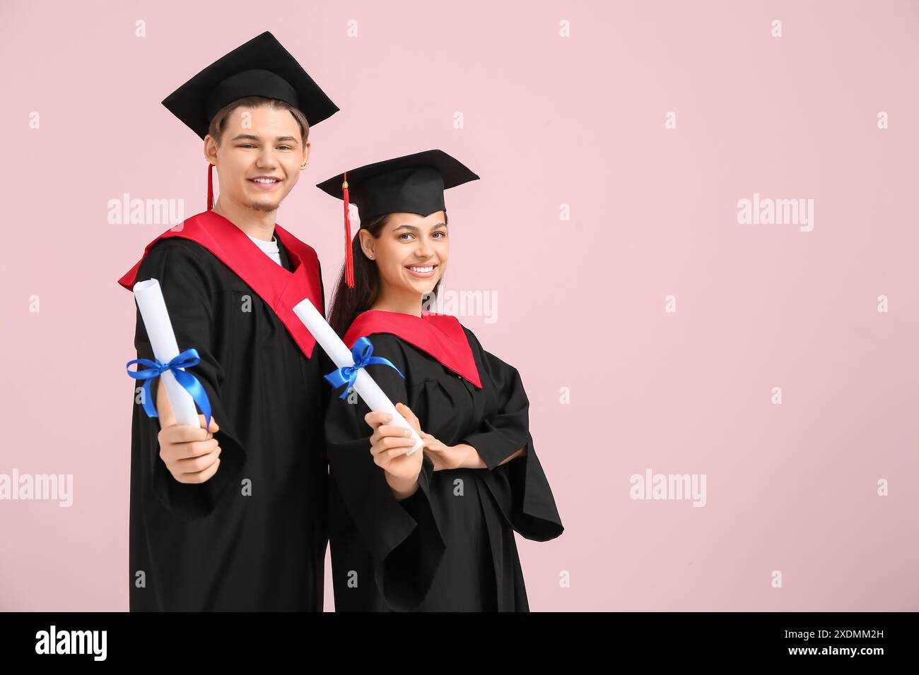 Happy graduate couple with diplomas on pink background Stock Photo - Alamy