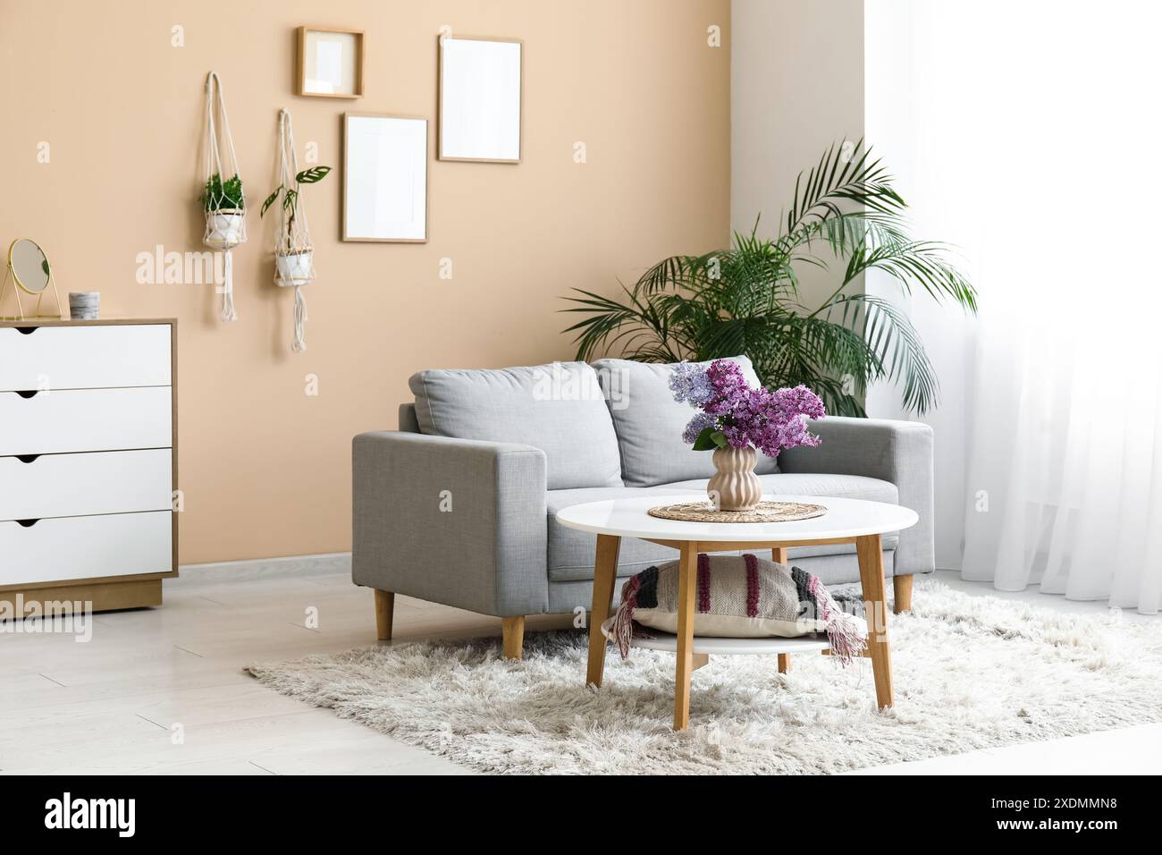 Interior of living room with bouquet of lilacs branches on coffee table ...