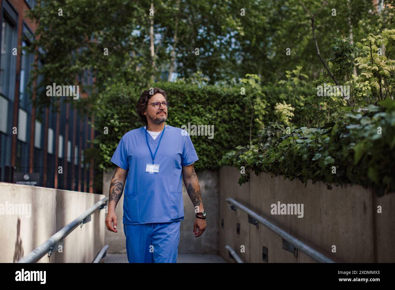 Doctor in uniform going home from work, walking in front of hospital ...