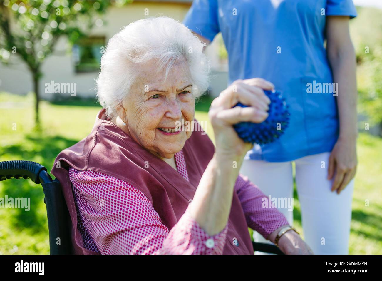 Female caregiver doing motorized exercises with senior woman in ...