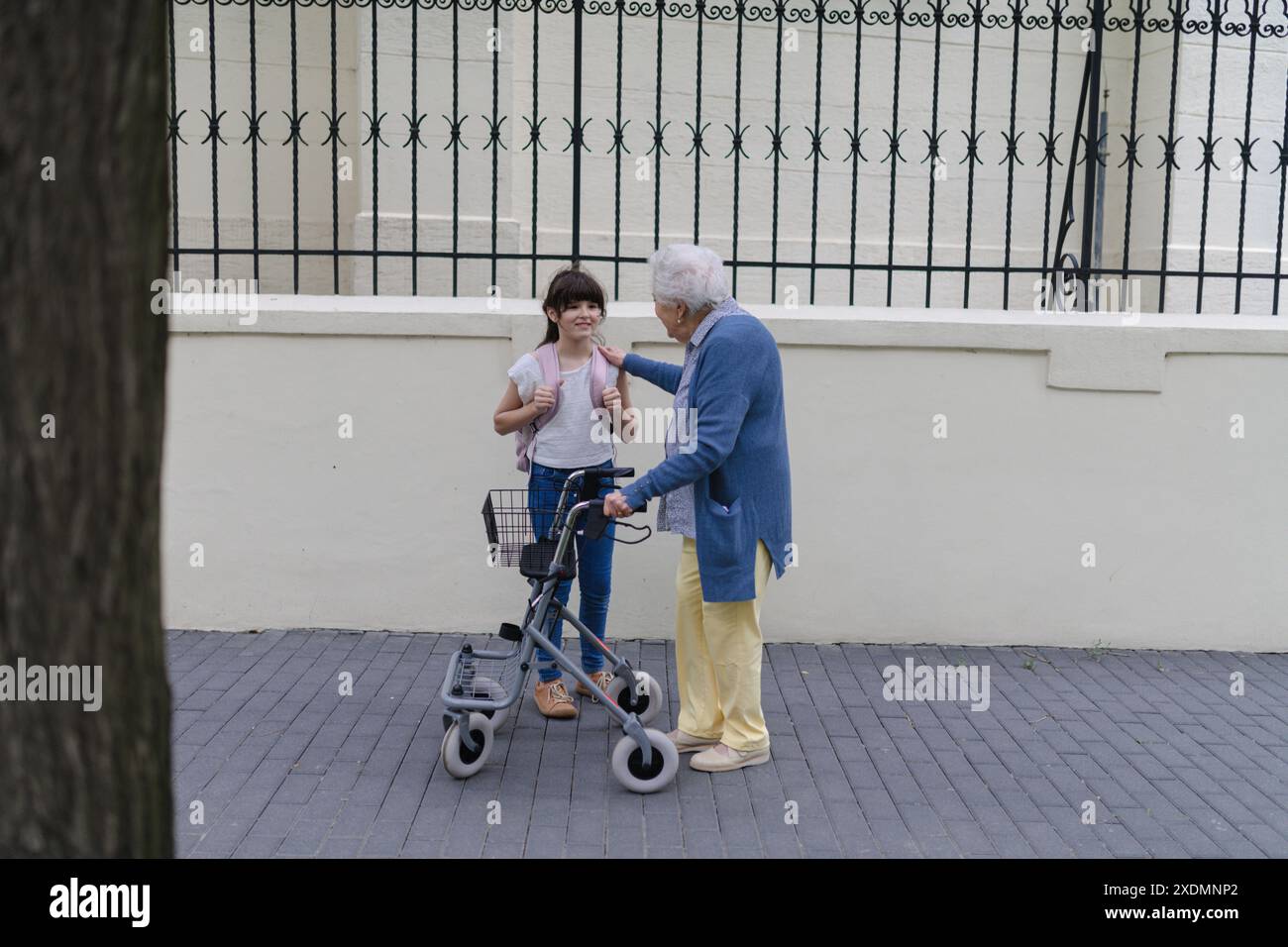 Grandma with walker picking up young girl from school at afternoon ...