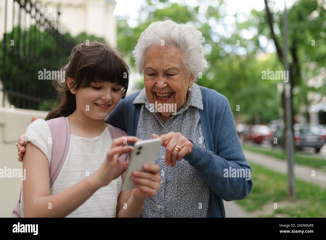 Grandma picking up young girl from school at afternoon. Granddaughter ...
