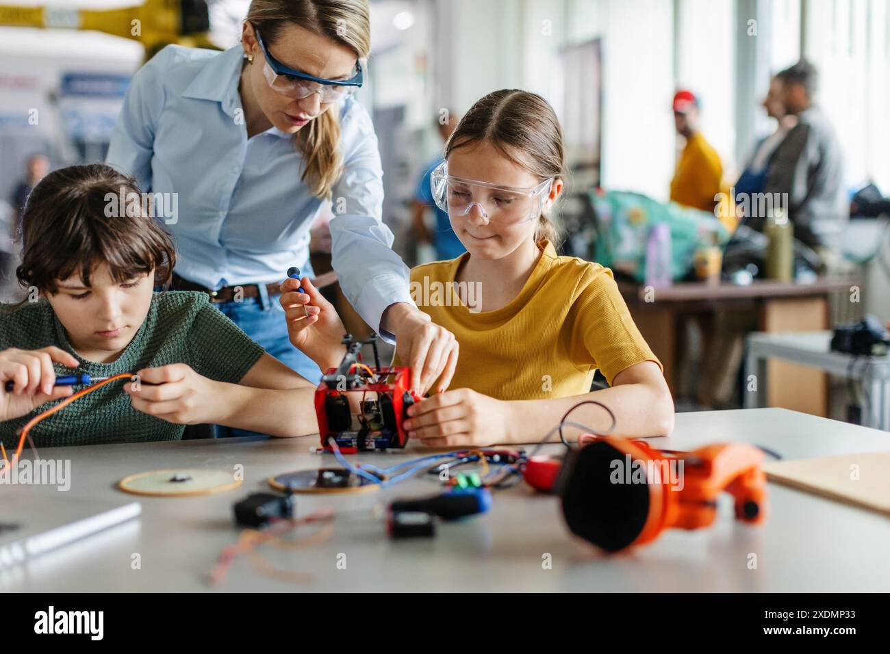 Female teacher helping to girls working on small robot, building ...