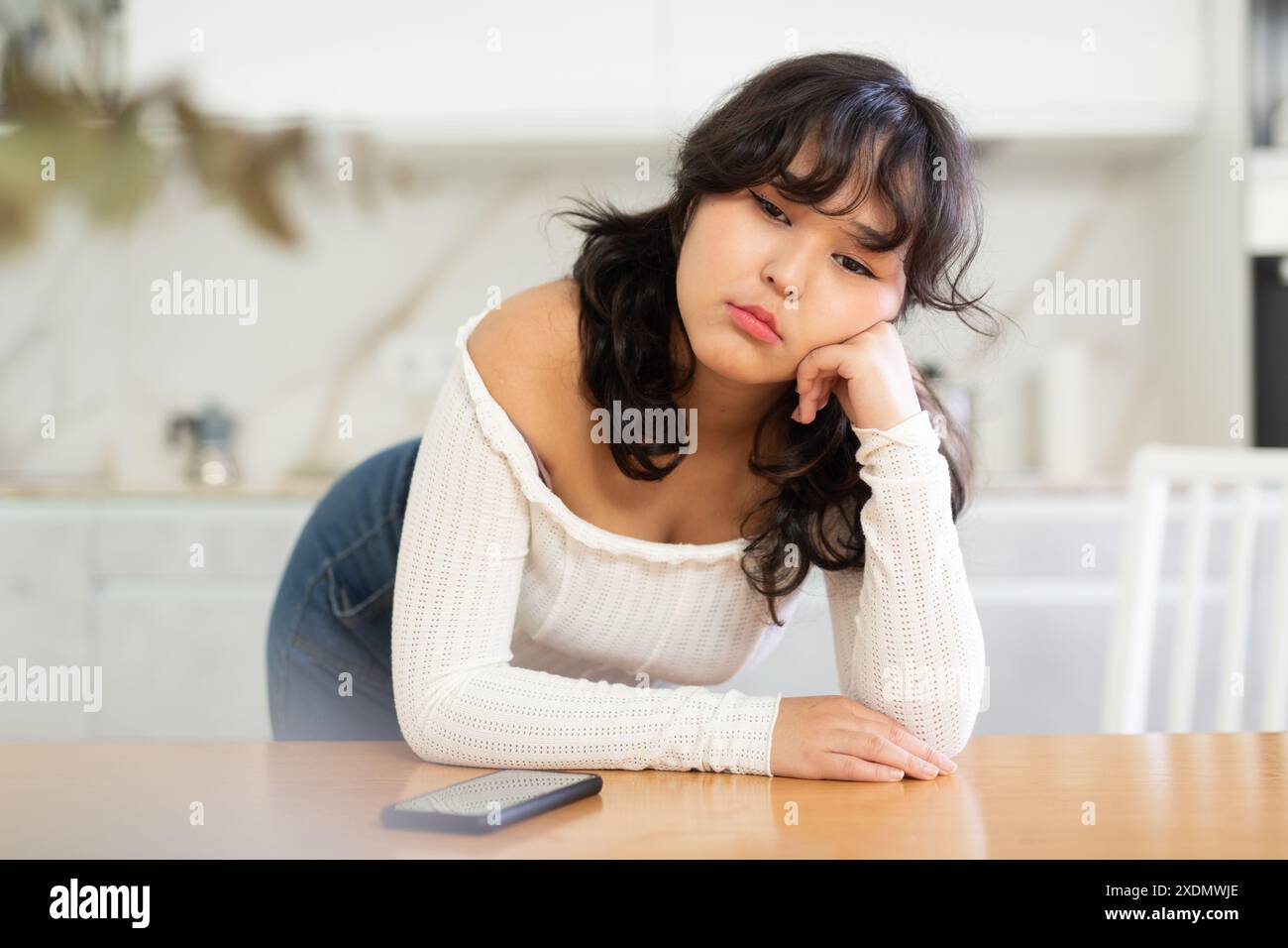 Sad young girl waiting for call from boyfriend in home interior Stock ...
