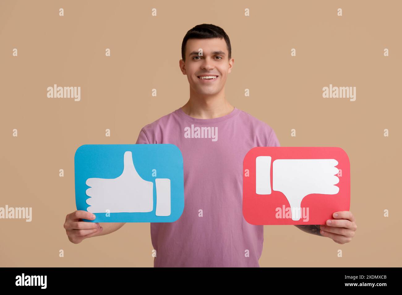 Handsome young happy man with like and dislike icons on beige ...